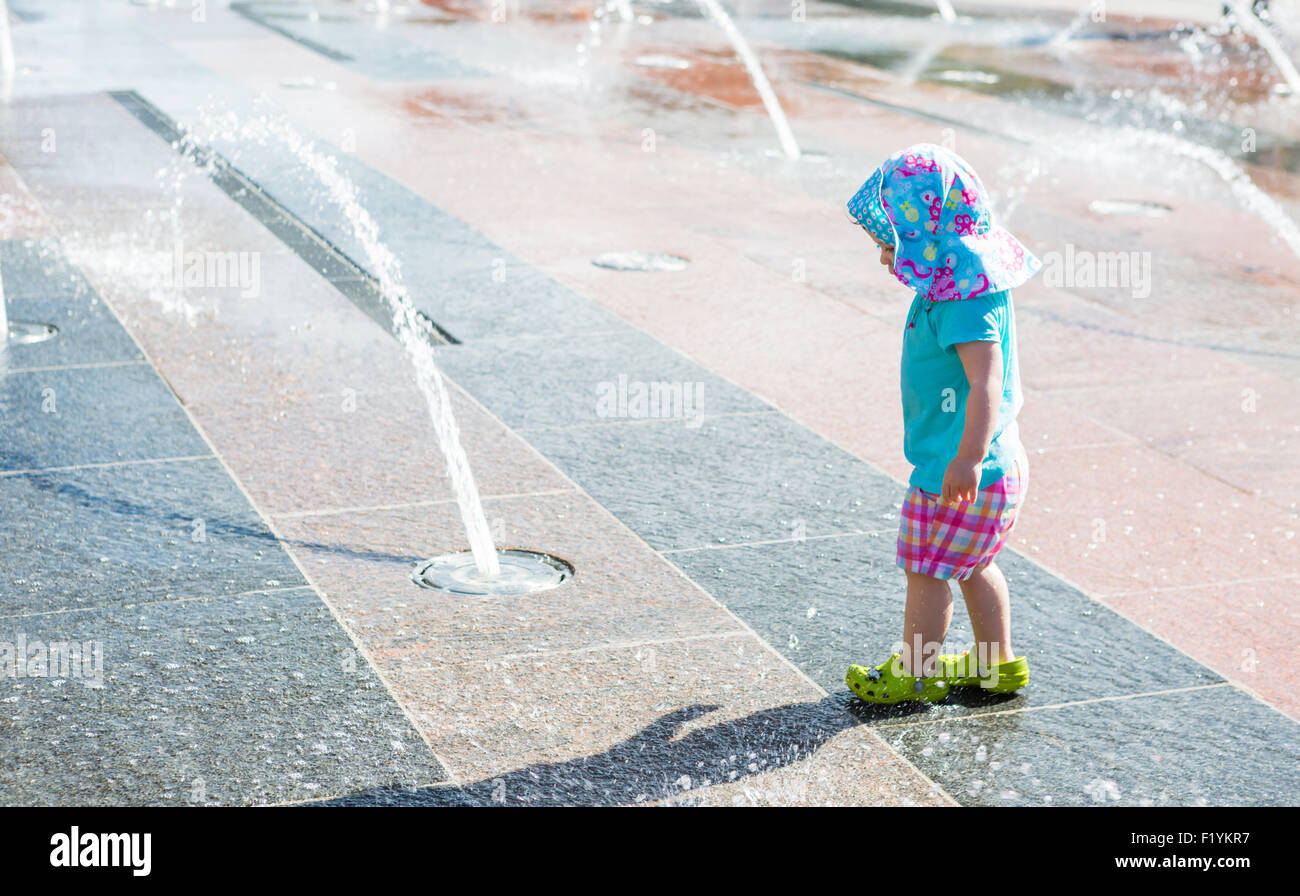 Cute toddler girl playing with small fountains in splash park Stock ...