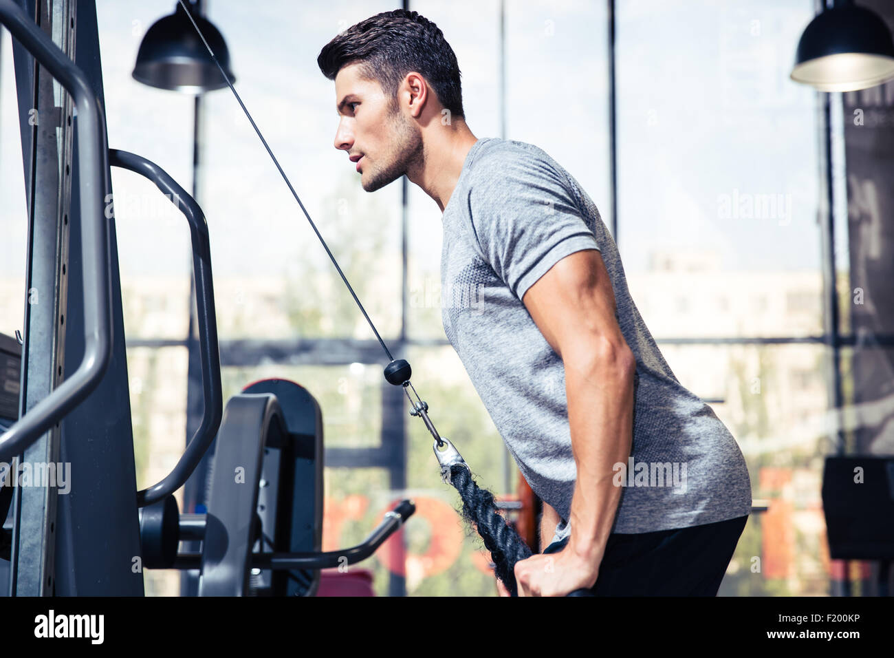 Side view portrait of a handsome man workout on fitness machine in gym ...