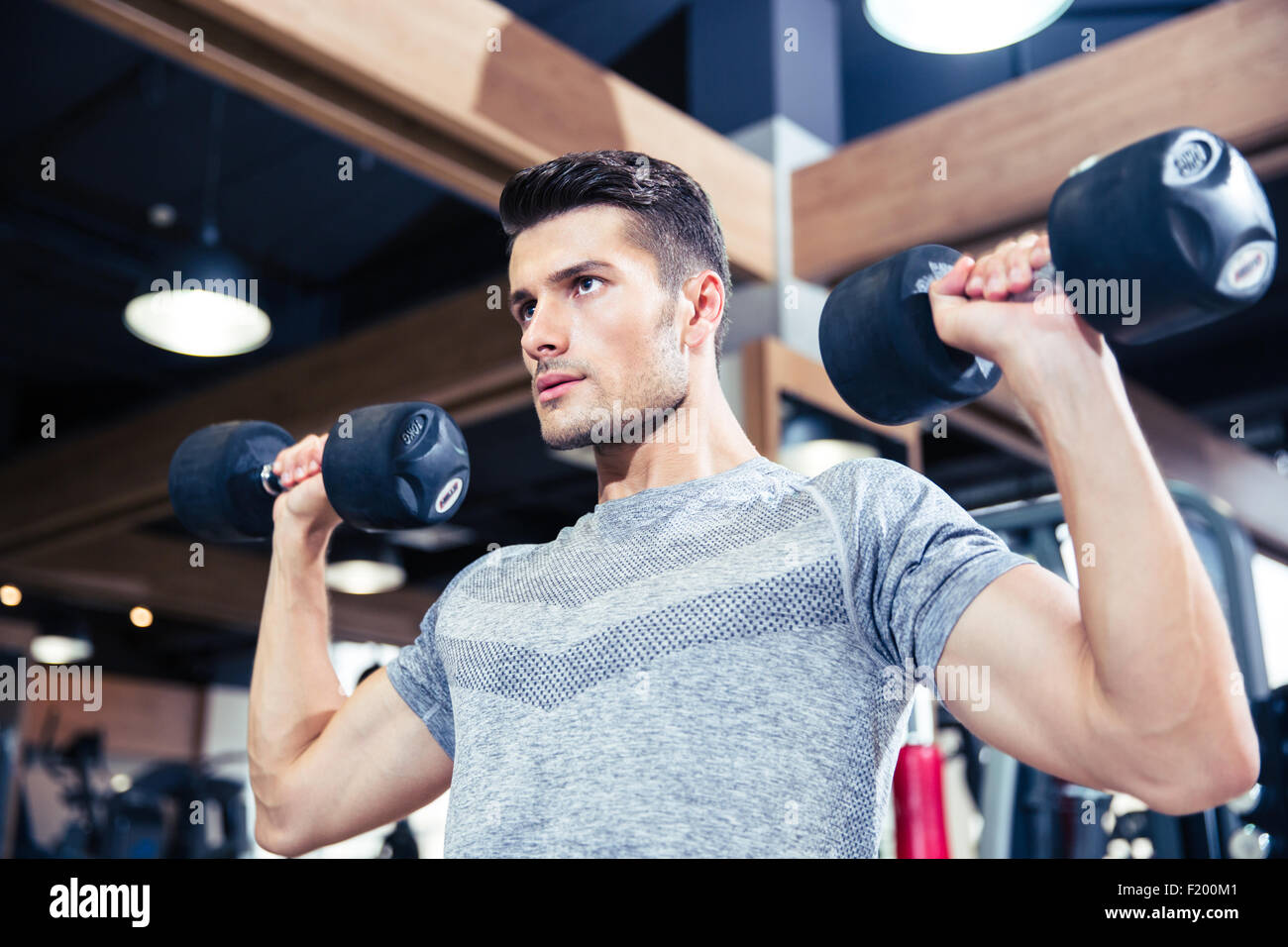 Portrait of a fitness man doing exercises with dumbbells at gym Stock ...