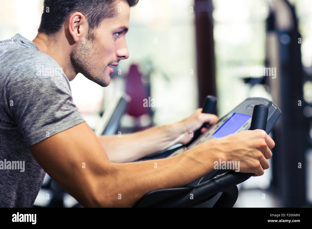 Handsome man workout on a fitness machine at gym Stock Photo - Alamy