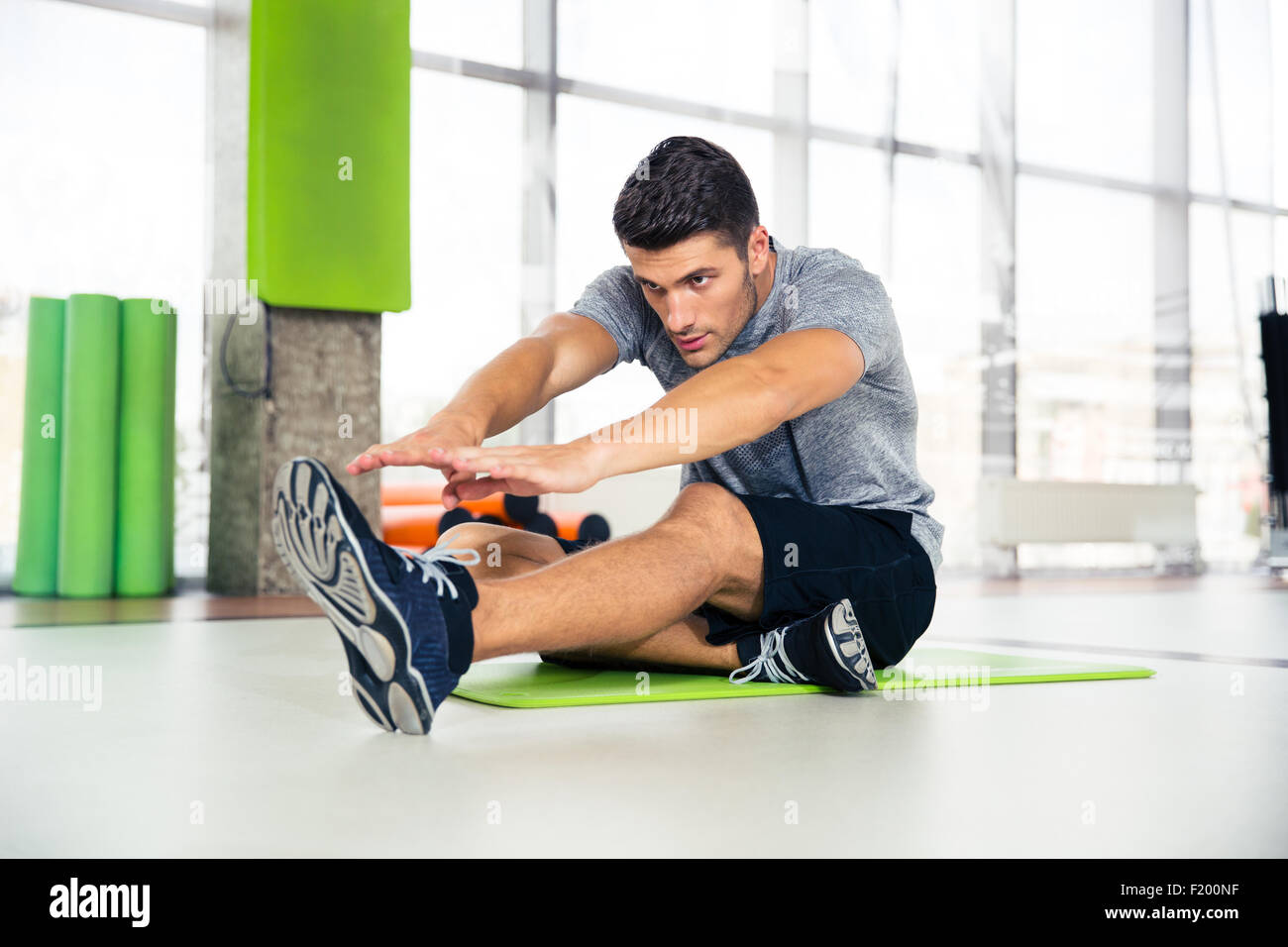 Portrait of a fitness man doing stretching exercises at gym Stock Photo ...