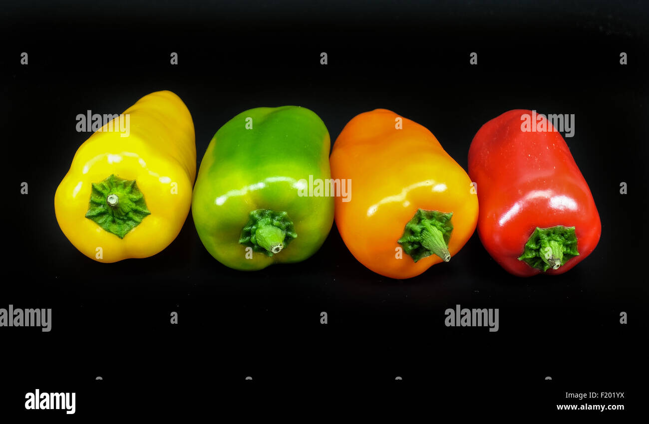 Four freshly picked peppers in yellow, green, orange and red colors ...