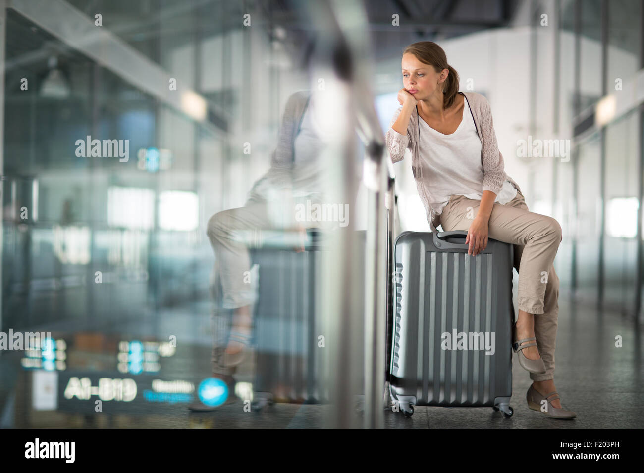 Young female passenger at the airport, about to check-in Stock Photo ...