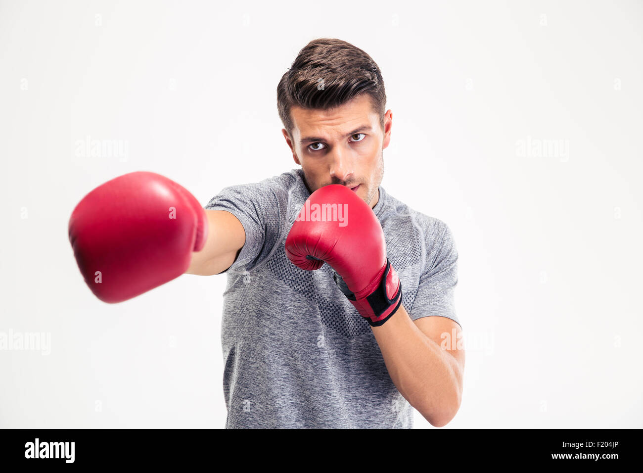 Portrait of a young man hitting at camera in boxing gloves isolated on ...