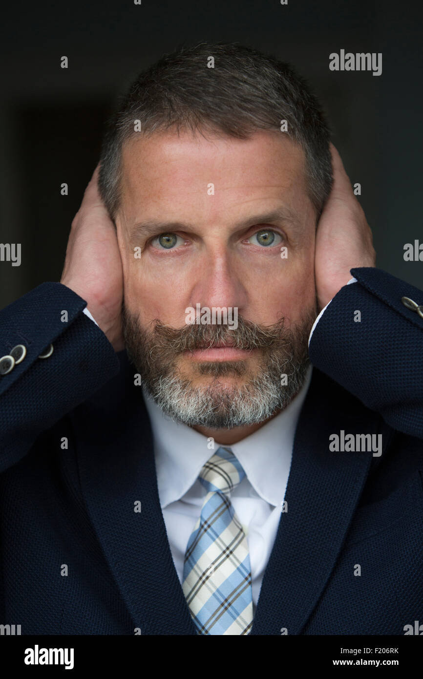 portrait of handsome businessman with beard and covering his ears Stock ...