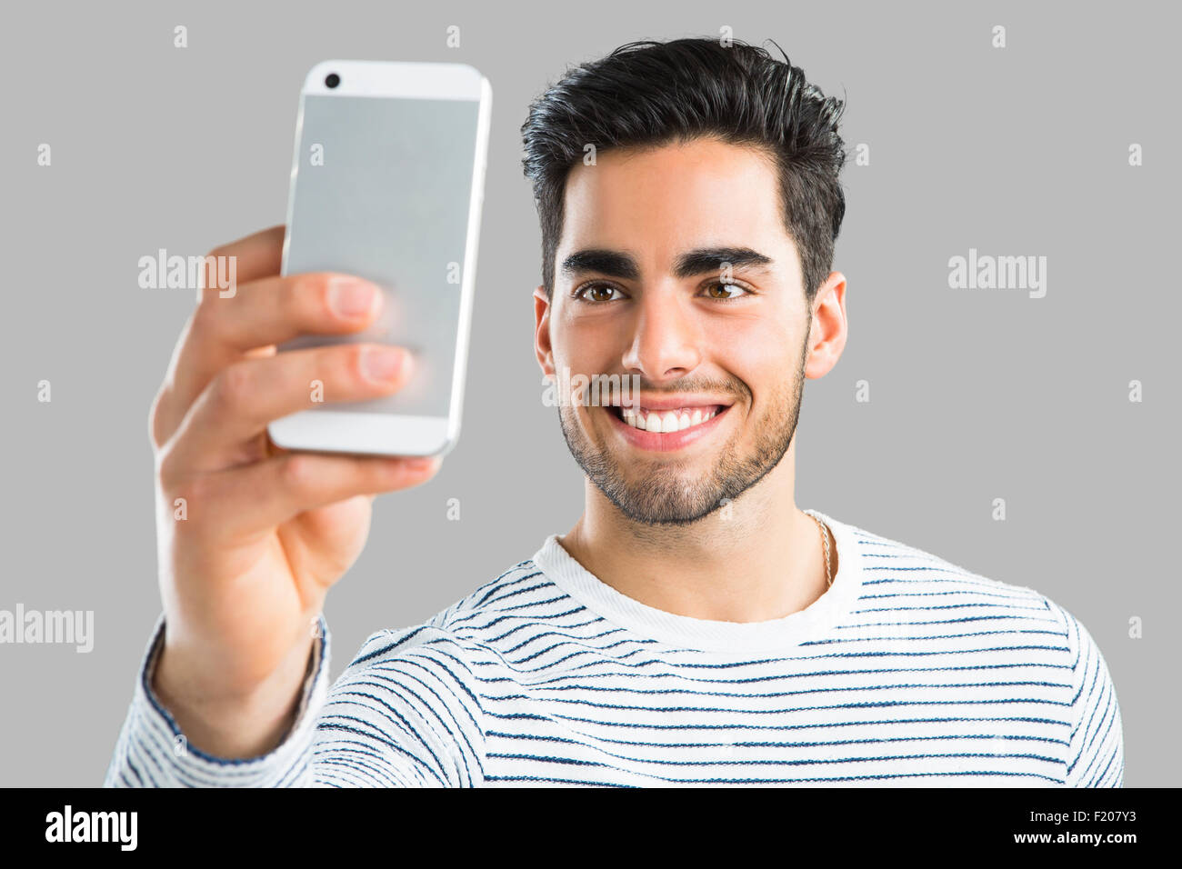 Handsome young man making a selfie picture with phone, isolated over ...