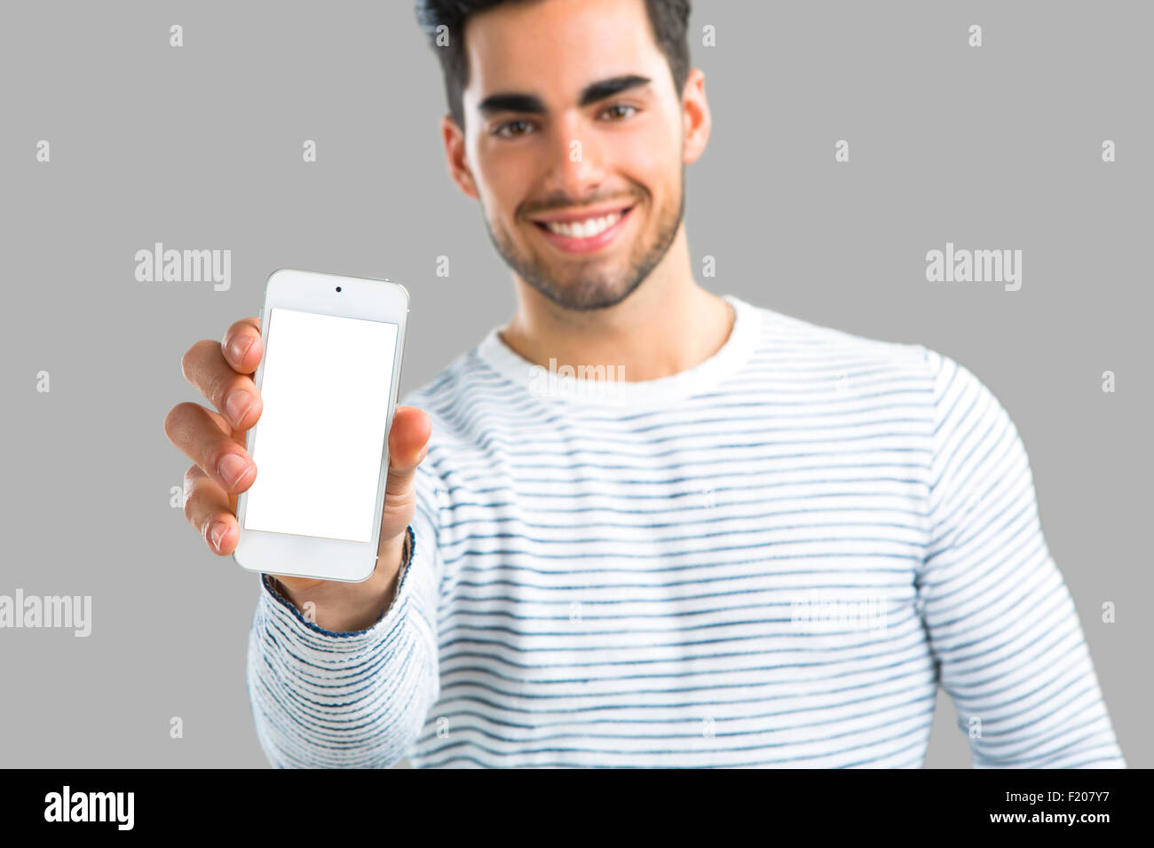Handsome young man showing something on his phone, isolated over gray ...