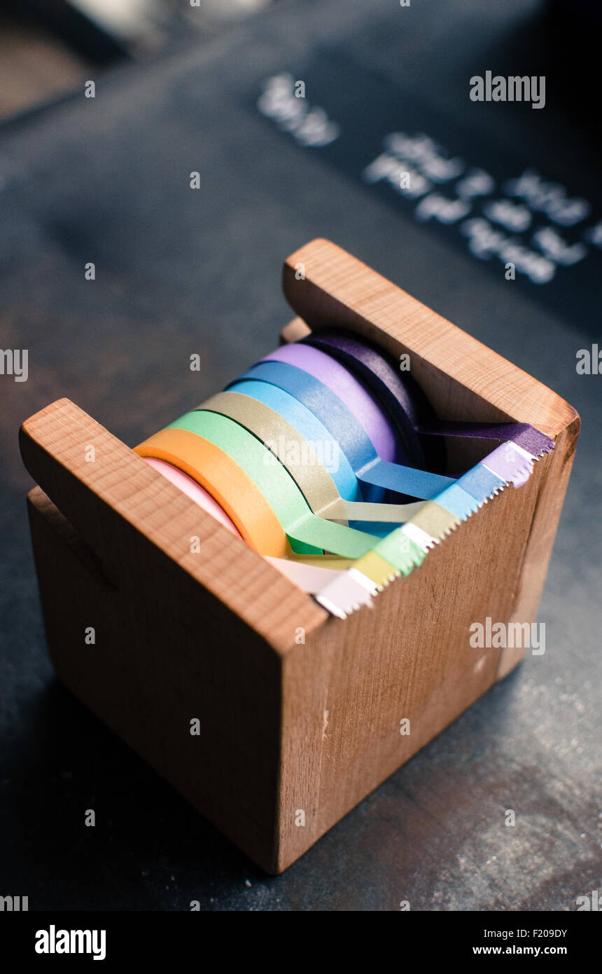 A wooden scotch tape dispenser with many colored tapes Stock Photo - Alamy
