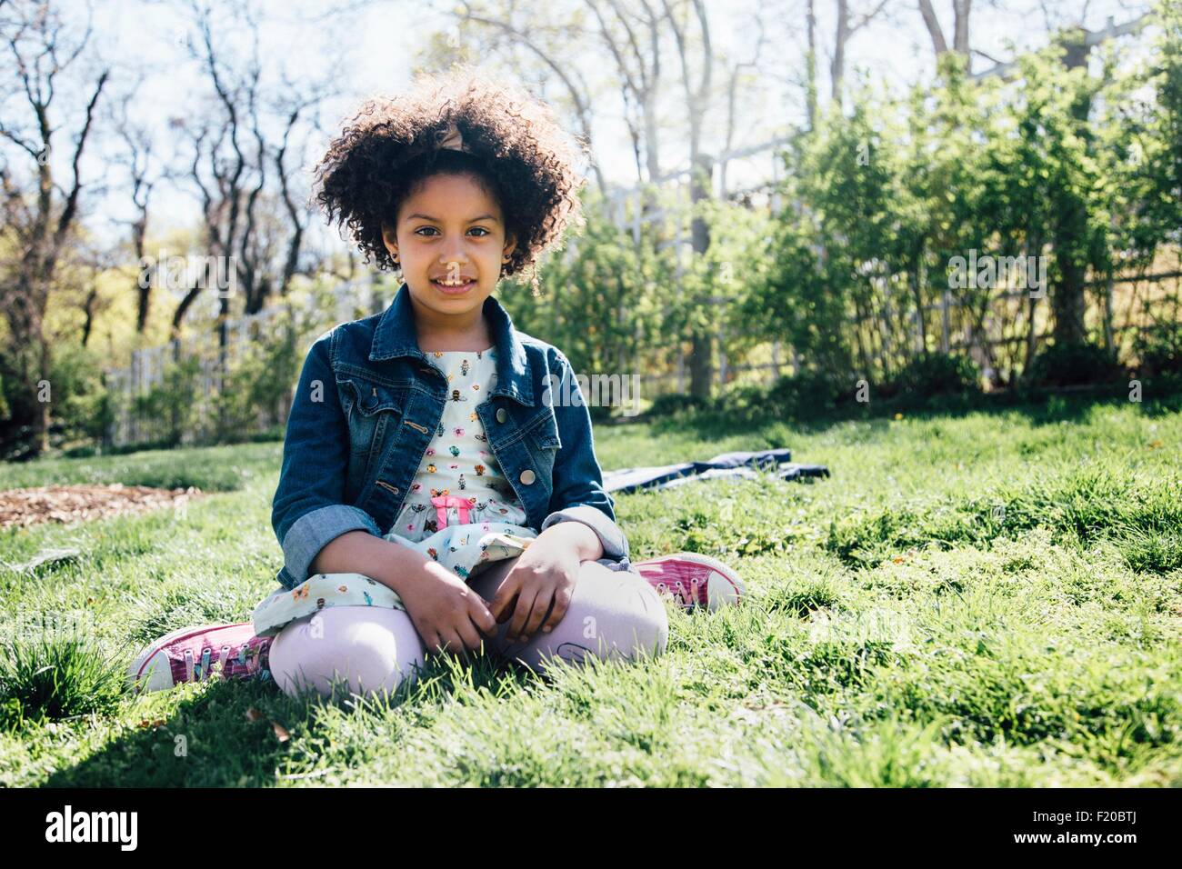 Front view of girl sitting on grass, looking at camera Stock Photo - Alamy