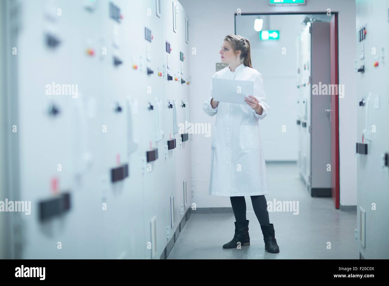 Young female scientist holding paperwork monitoring machine in ...