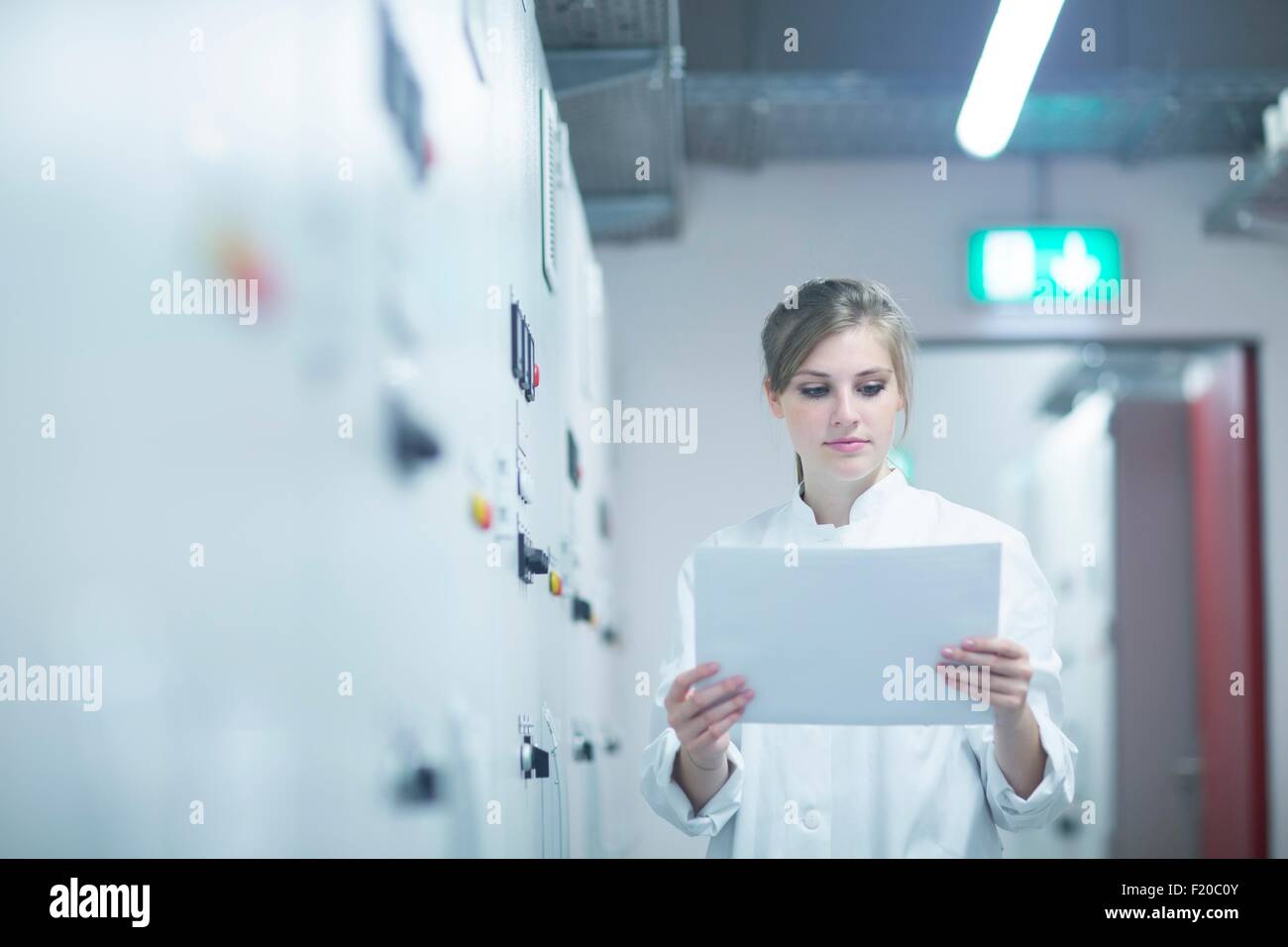Young female scientist reading paperwork in technical room Stock Photo ...