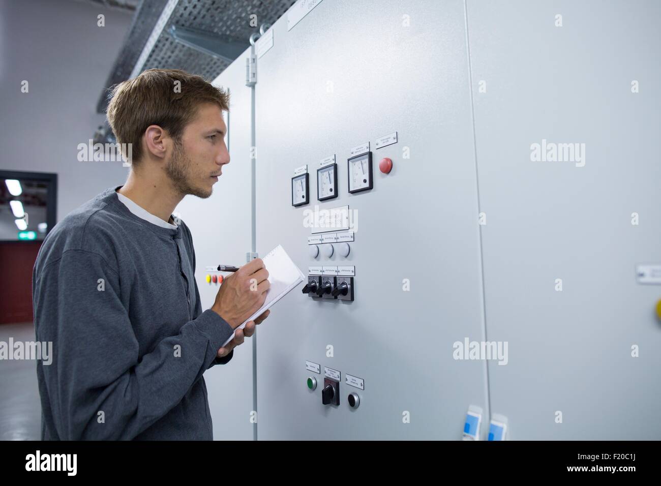 Young male technician making notes in technical room Stock Photo - Alamy