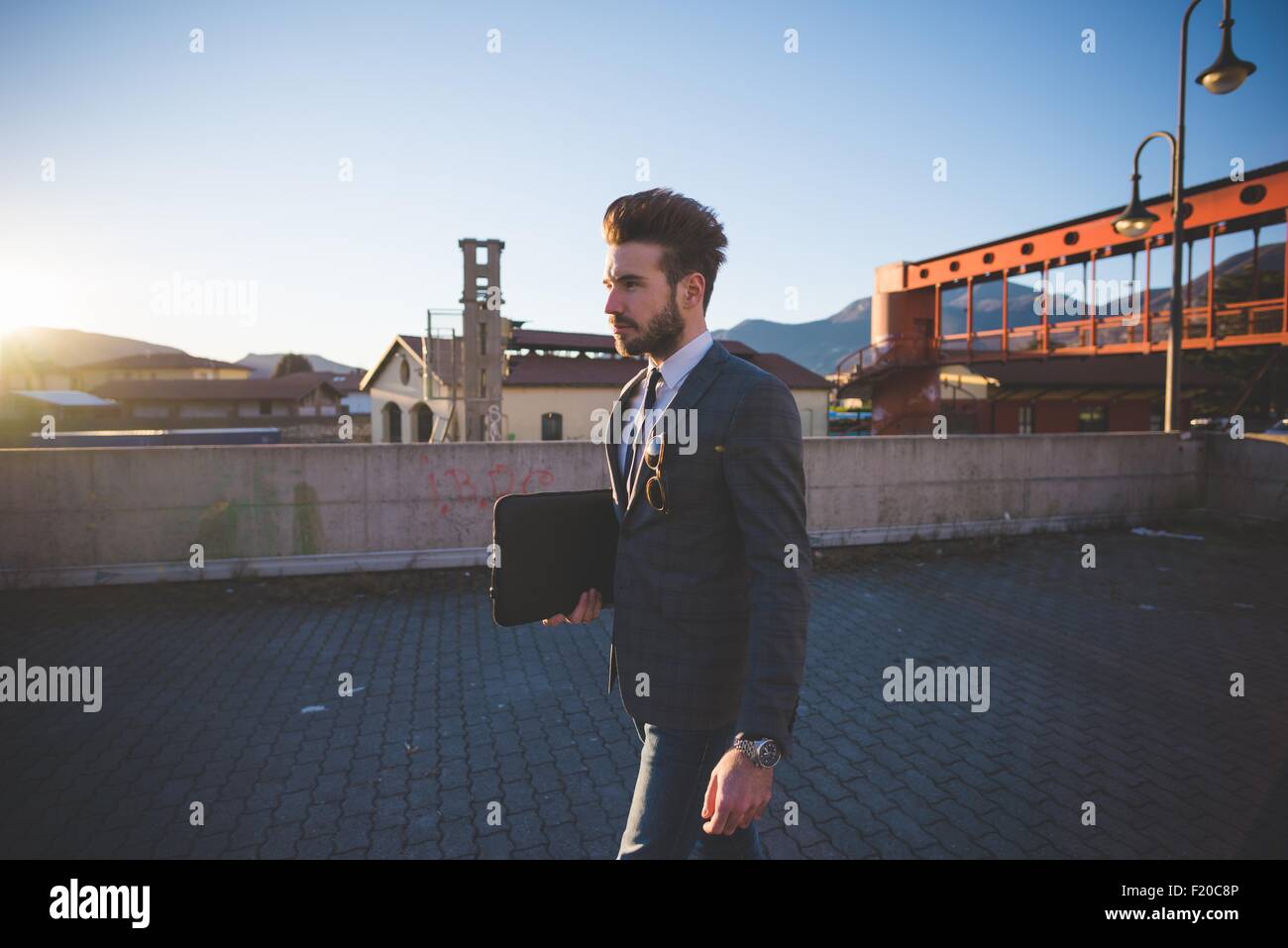 Young businessman carrying briefcase in urban area Stock Photo - Alamy