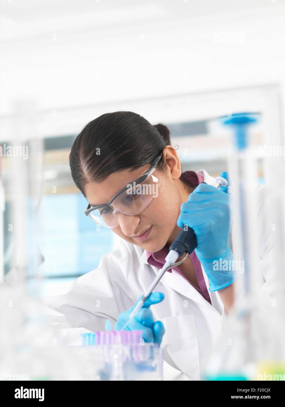 Young woman scientist pipetting sample into vial in a laboratory used ...