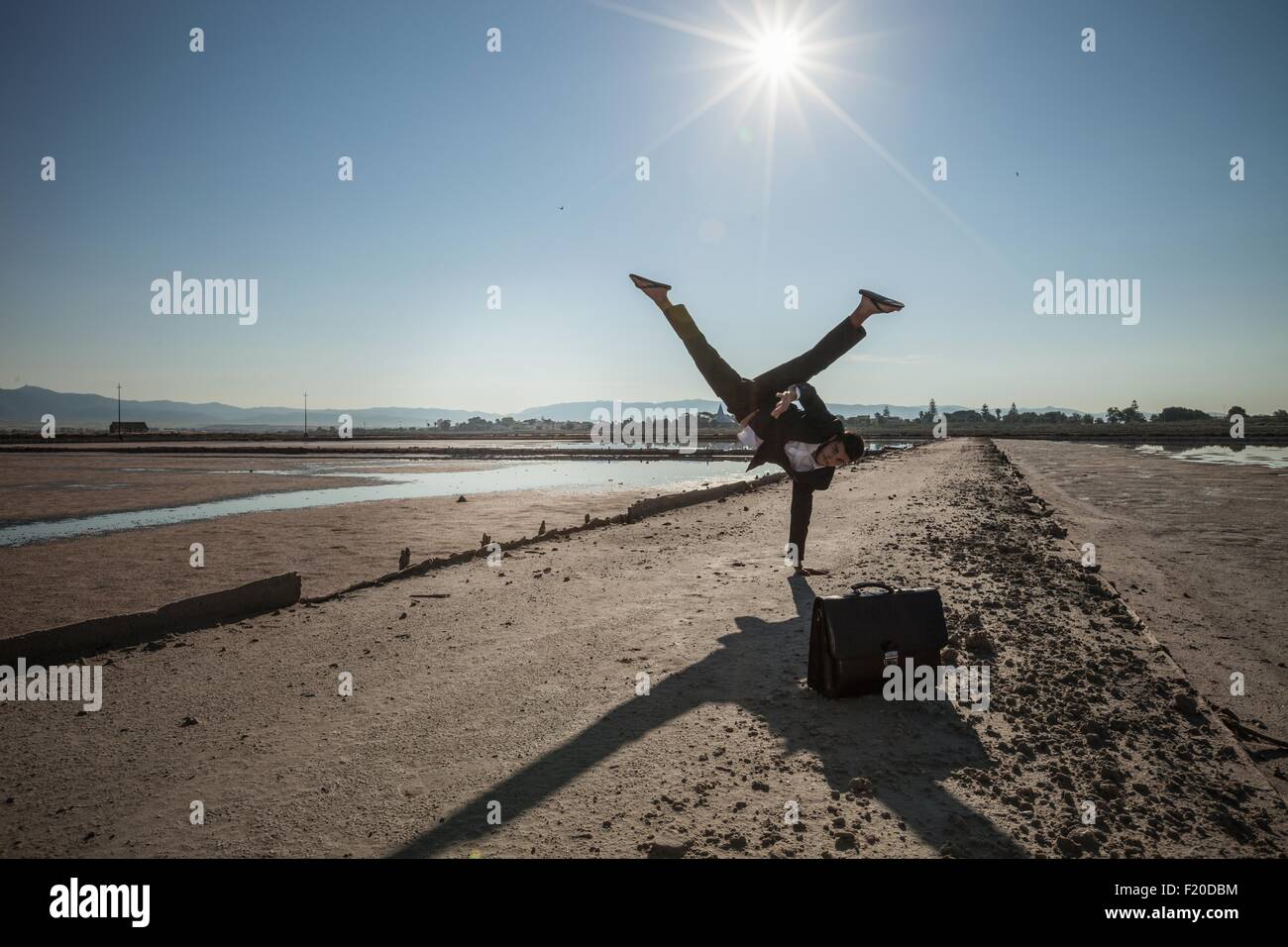 Mid adult businessman doing handstand on beach Stock Photo - Alamy
