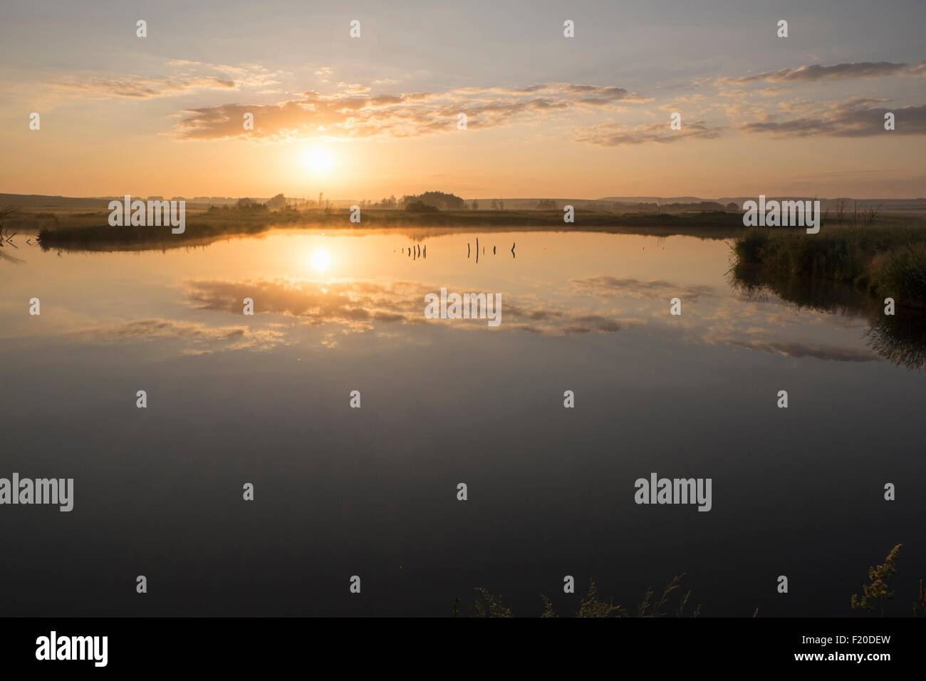 Silhouetted view of still lake at sunset Stock Photo - Alamy