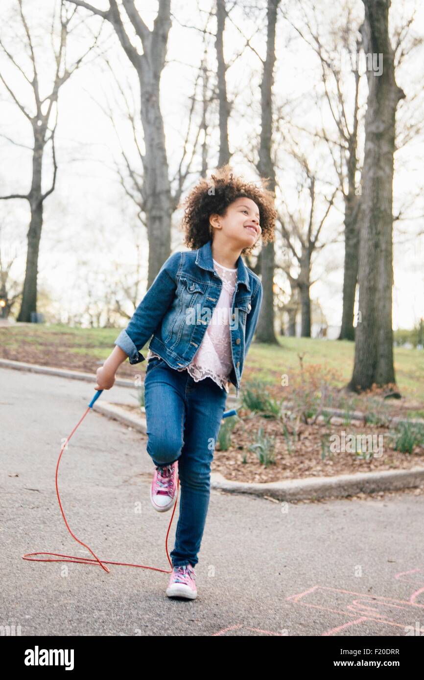 Girl standing on one leg, playing with skipping rope, looking up Stock ...
