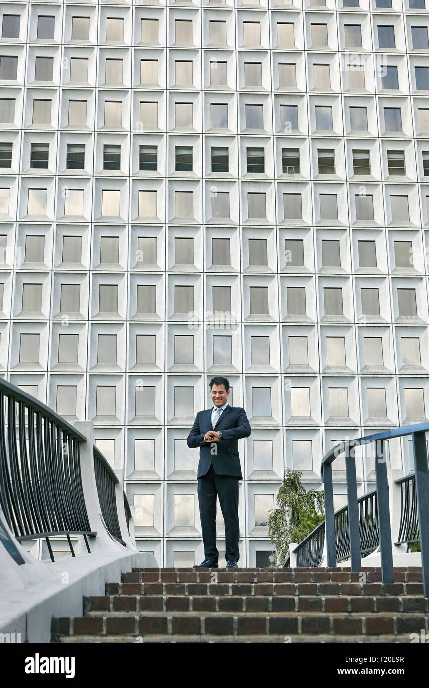 Low angle view of business man standing at top of stairway looking at ...