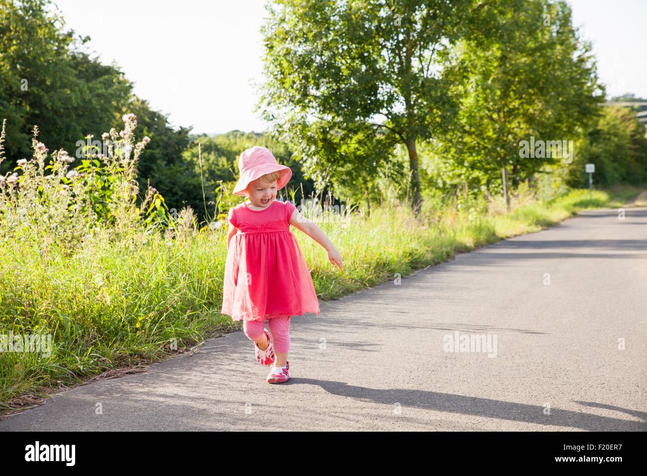 Female toddler watching her shadow toddling along rural road Stock ...