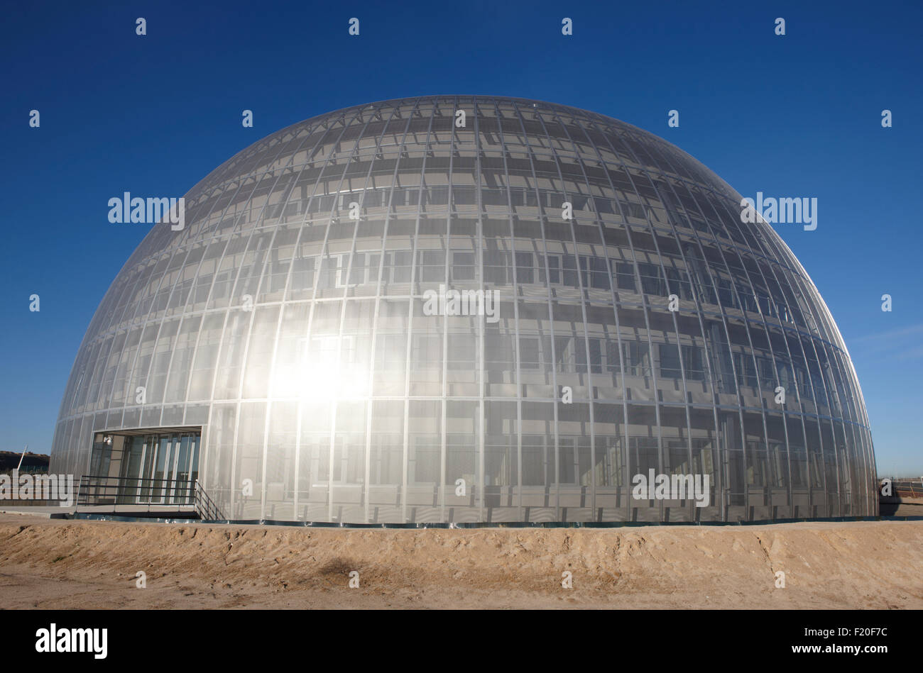 Metallic building circular on sandy ground with blue sky under ...