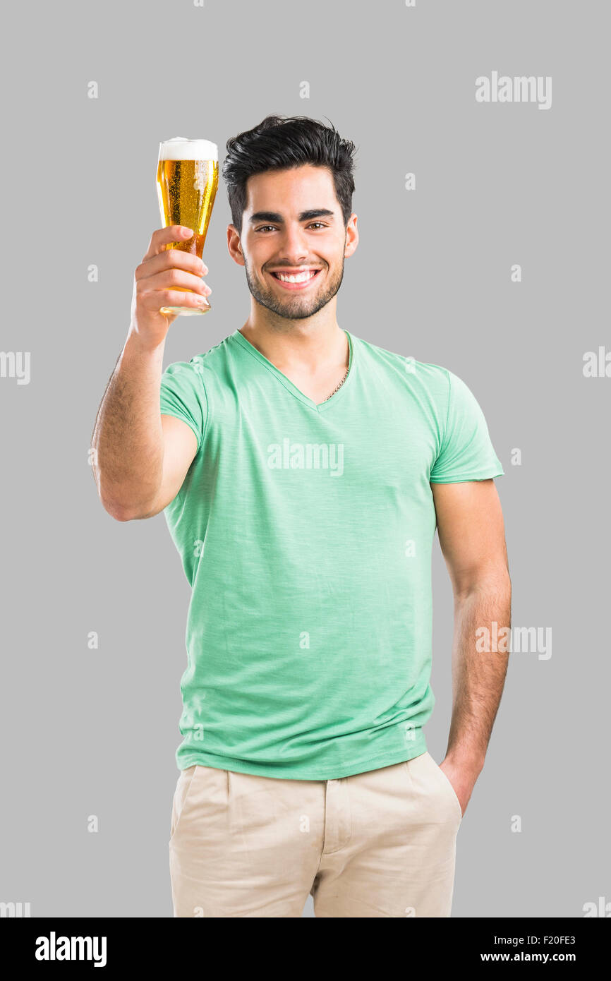 Portrait of handsome young man tasting a draft beer, isolated on gray ...