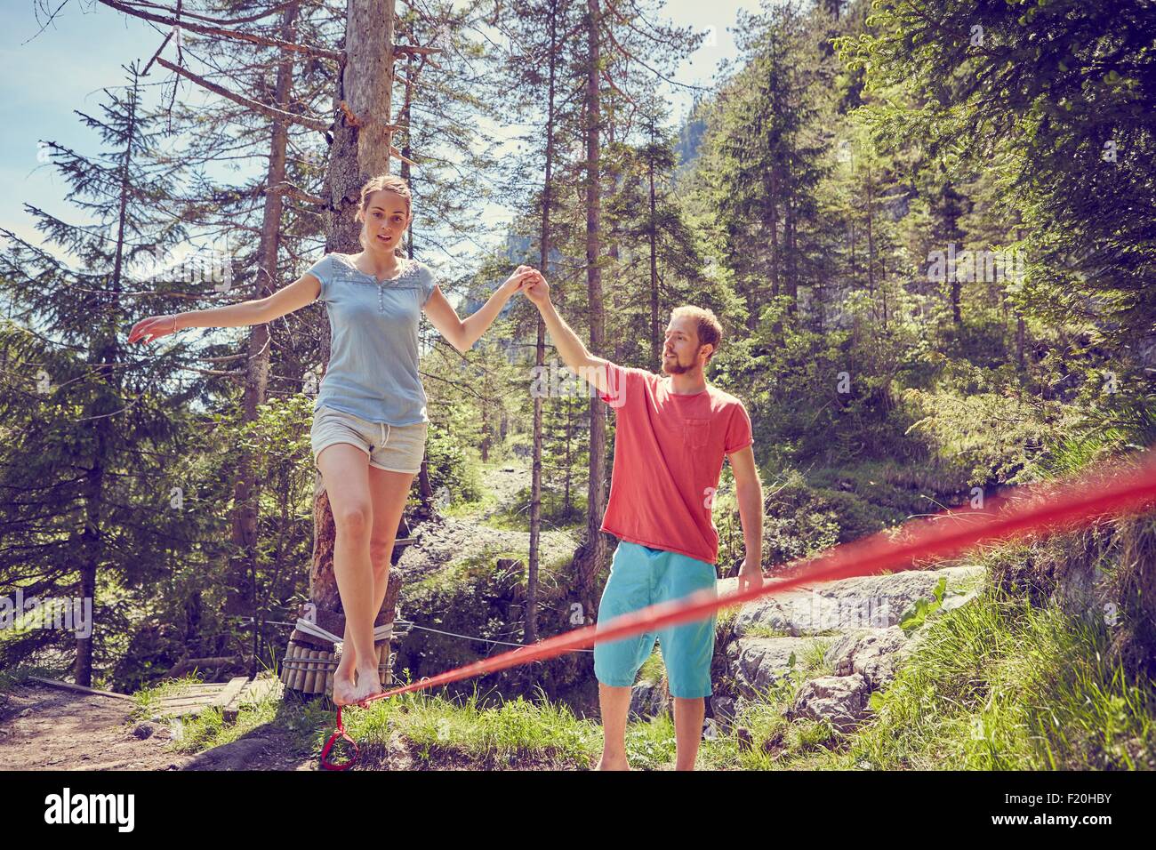 Woman balancing on rope with help from man, Ehrwald, Tyrol, Austria ...