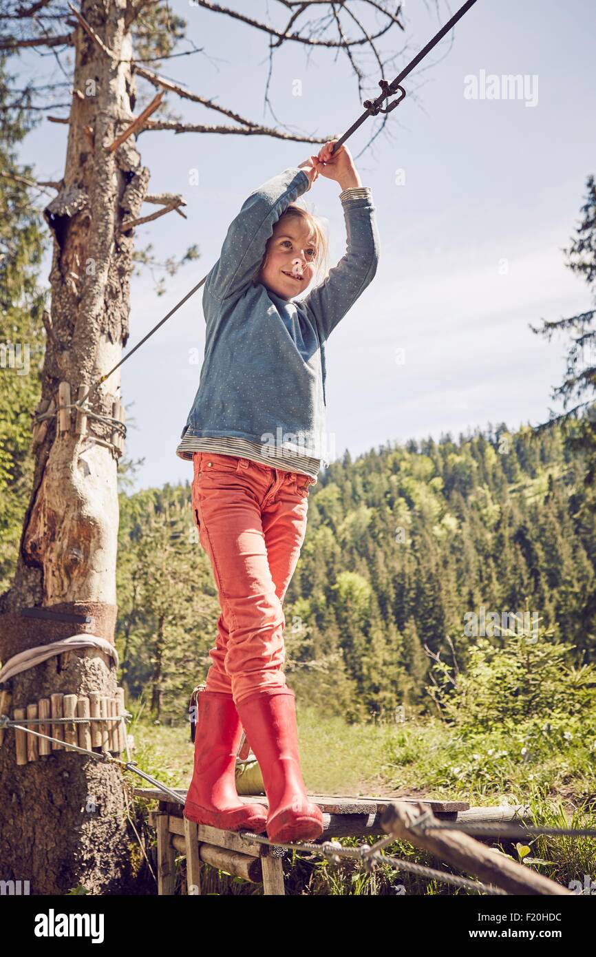 Young girl walking across single rope bridge Stock Photo - Alamy