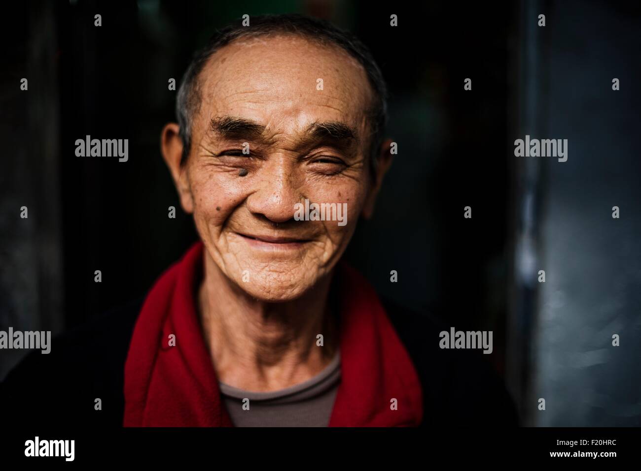 Portrait of senior man wearing red scarf around neck looking at camera ...