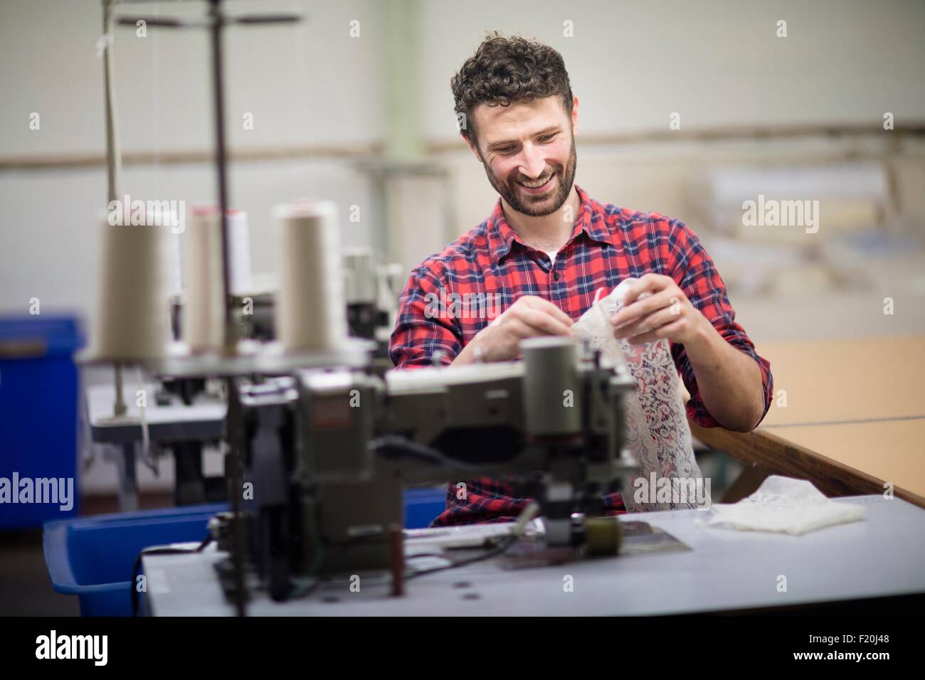 Male textile designer using sewing machine in old textile mill Stock ...