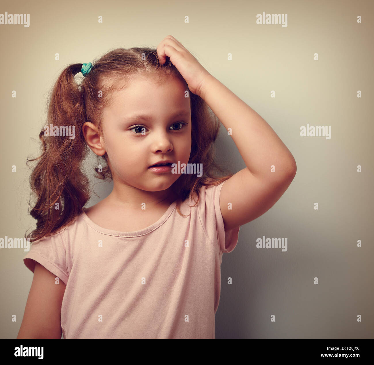 Cute thinking worried kid girl scratching the head and looking on empty ...