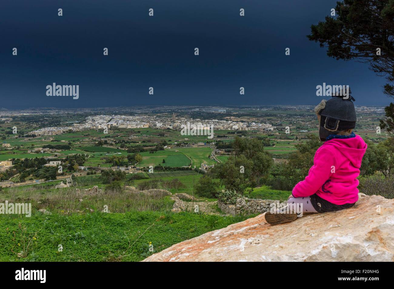Malta, Siggiewi, little girl sitting on a rock watching a rural ...