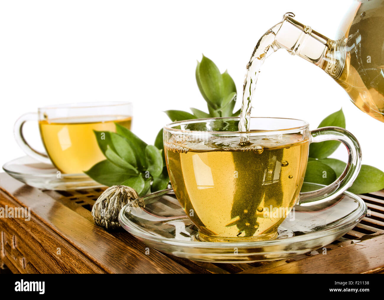 still life of the glass teapot flow green tea in cup on white ...