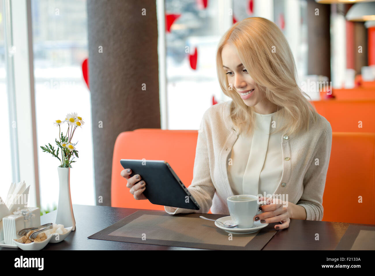 Very beautiful, happy, young woman, sit in Cafe with flatbed computer ...