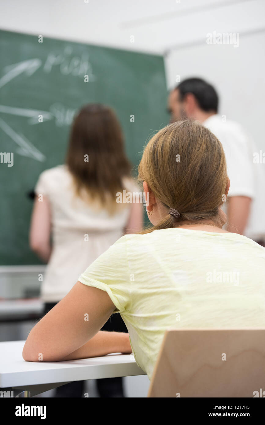 female college student looking at blackboard while another student ...