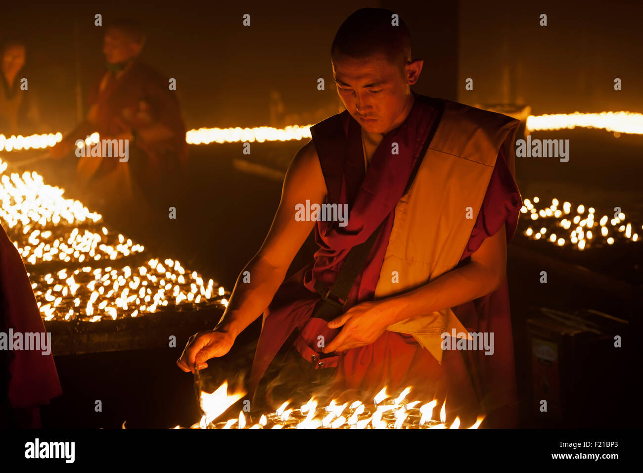 India, Bihar, Bodhgaya, Buddhist monk lighting merit-making candles in ...