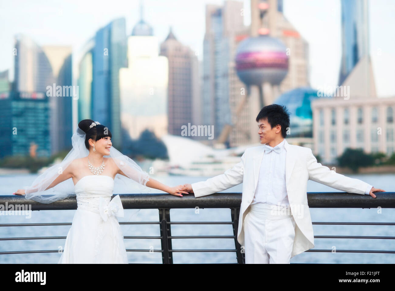Chinese couple wearing modern white wedding attire look at each other ...