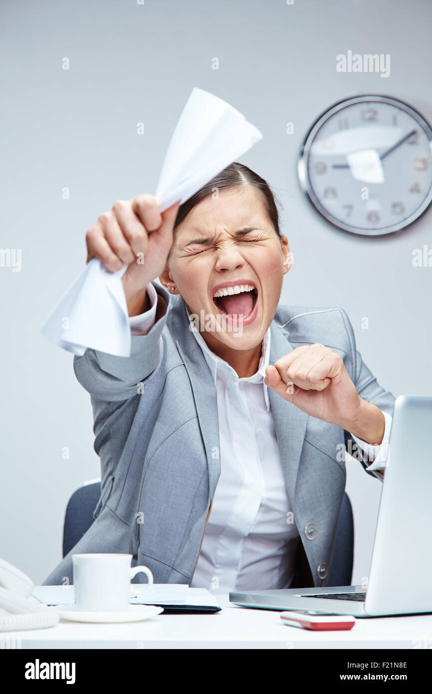 Stressed businesswoman with creased paper shouting at workplace Stock ...
