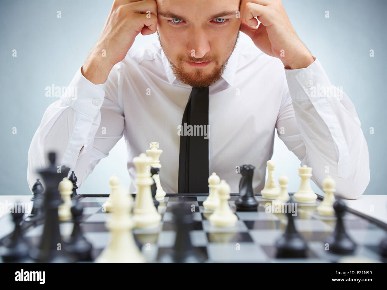 Pensive businessman leaning over chessboard Stock Photo - Alamy