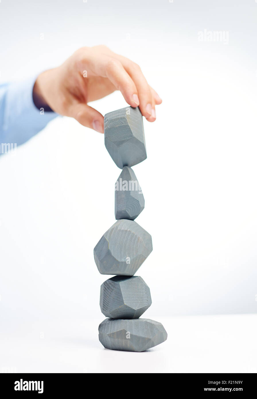 Human hand holding grey stone over stone tower Stock Photo - Alamy