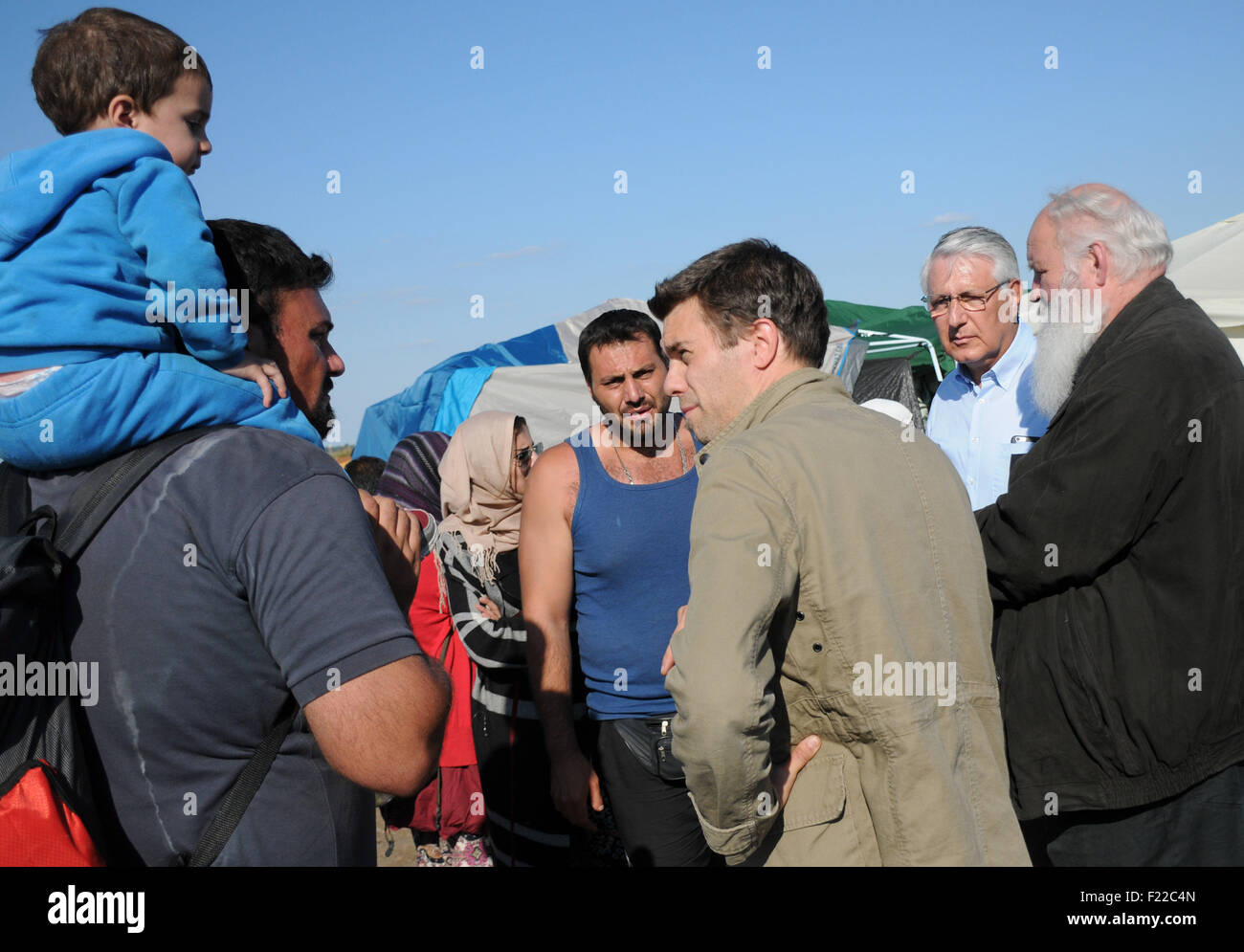Hungarian doctor Falus Ferenc (second from right)talks to refugees at ...