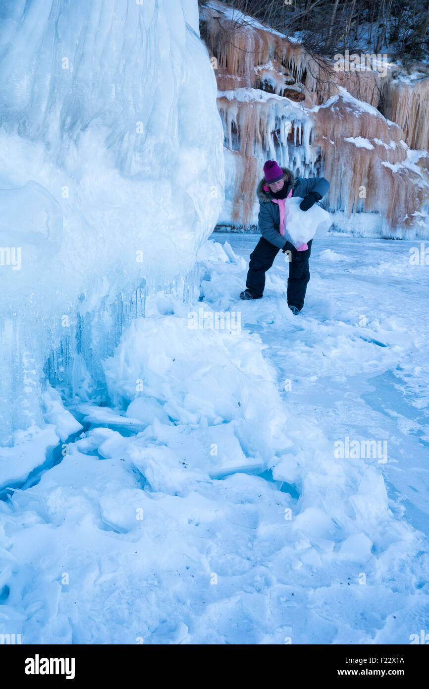 Woman lifts a large heavy piece of ice while visiting the ice caves at ...