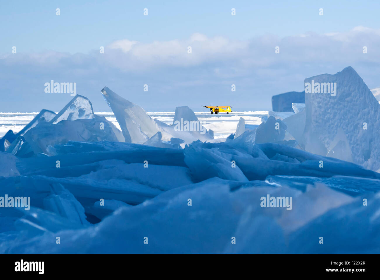 Low angle shot of plate ice jumbled on Lake Superior with yellow plane ...