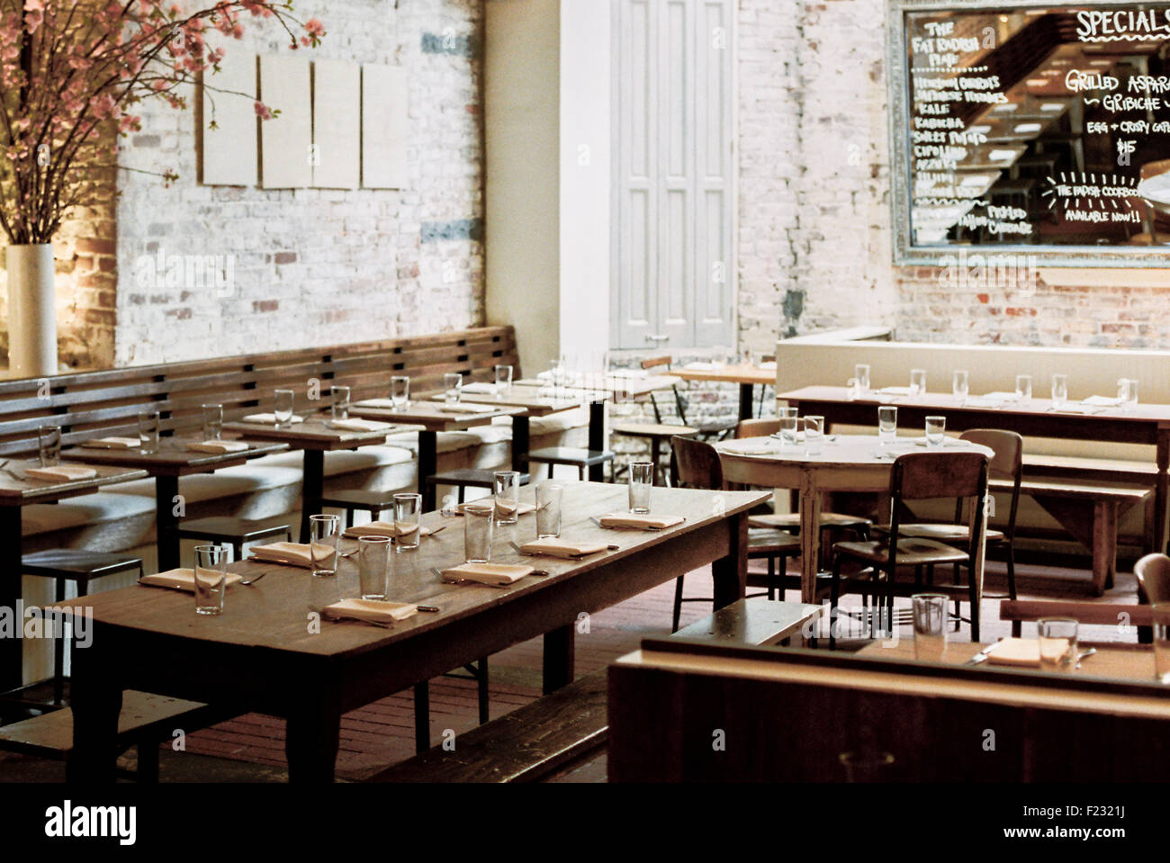 A restaurant with long narrow tables and chairs laid for a meal. A ...
