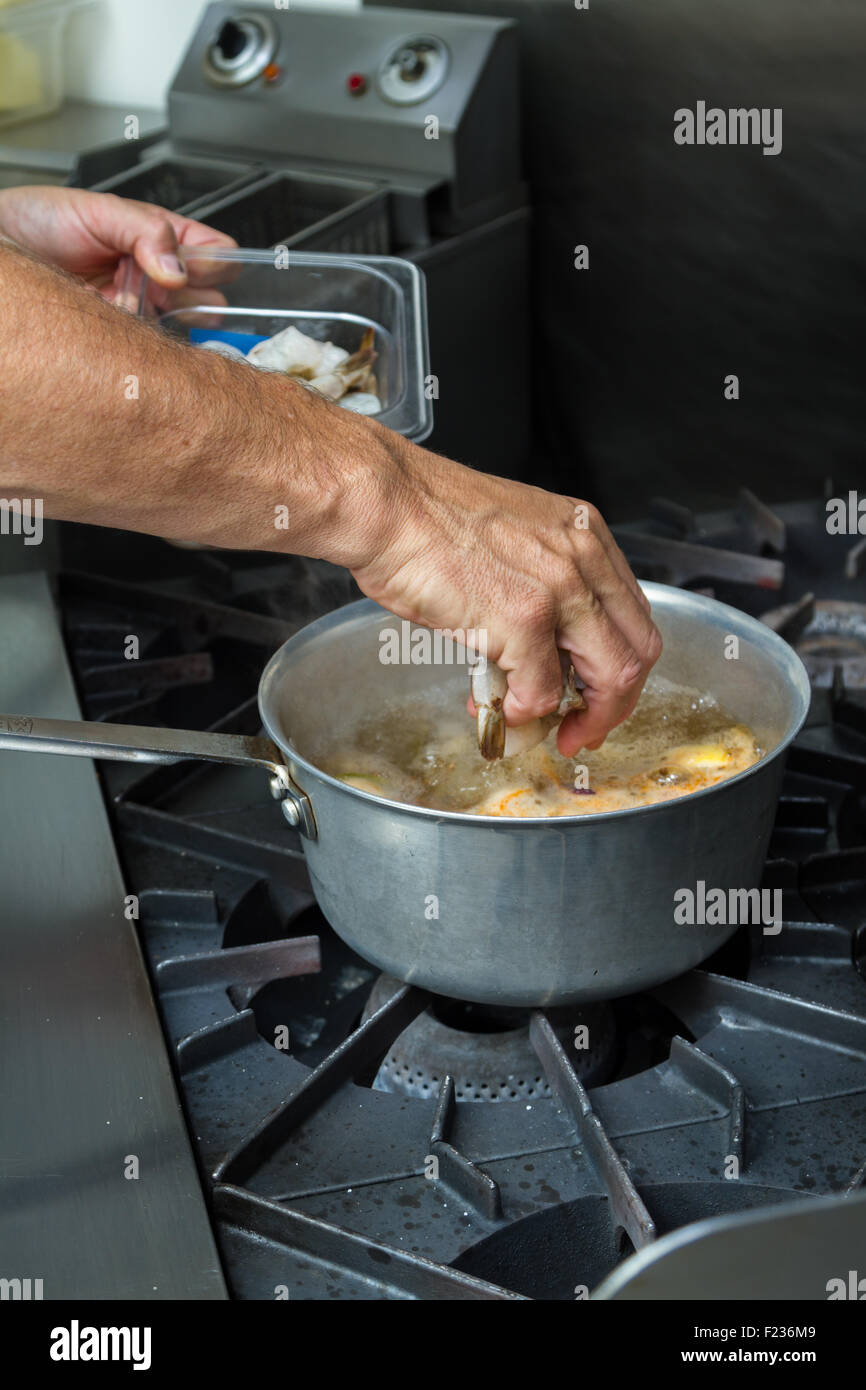 professional chef cooking shrimp using a base with aromas and spices ...