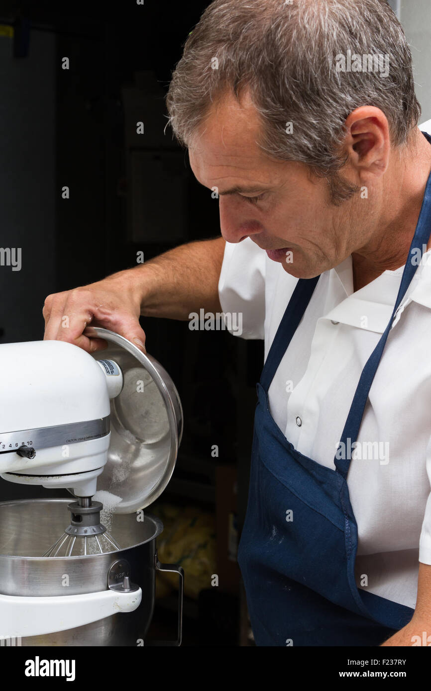 professional chef pouring ingredients into a mixer preparing for dinner ...
