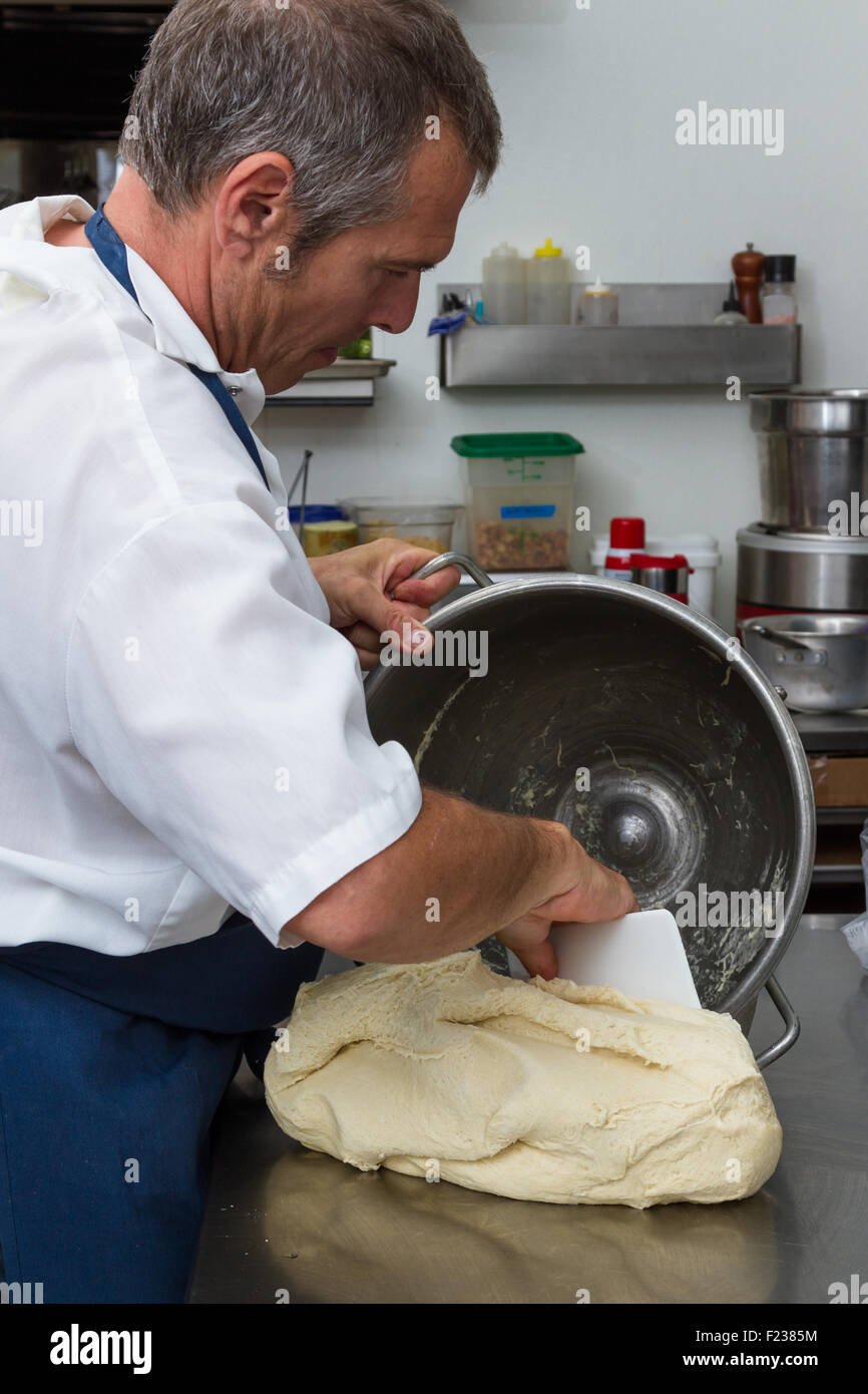 professional chef craping out fresh dough from a large mixing bowl ...