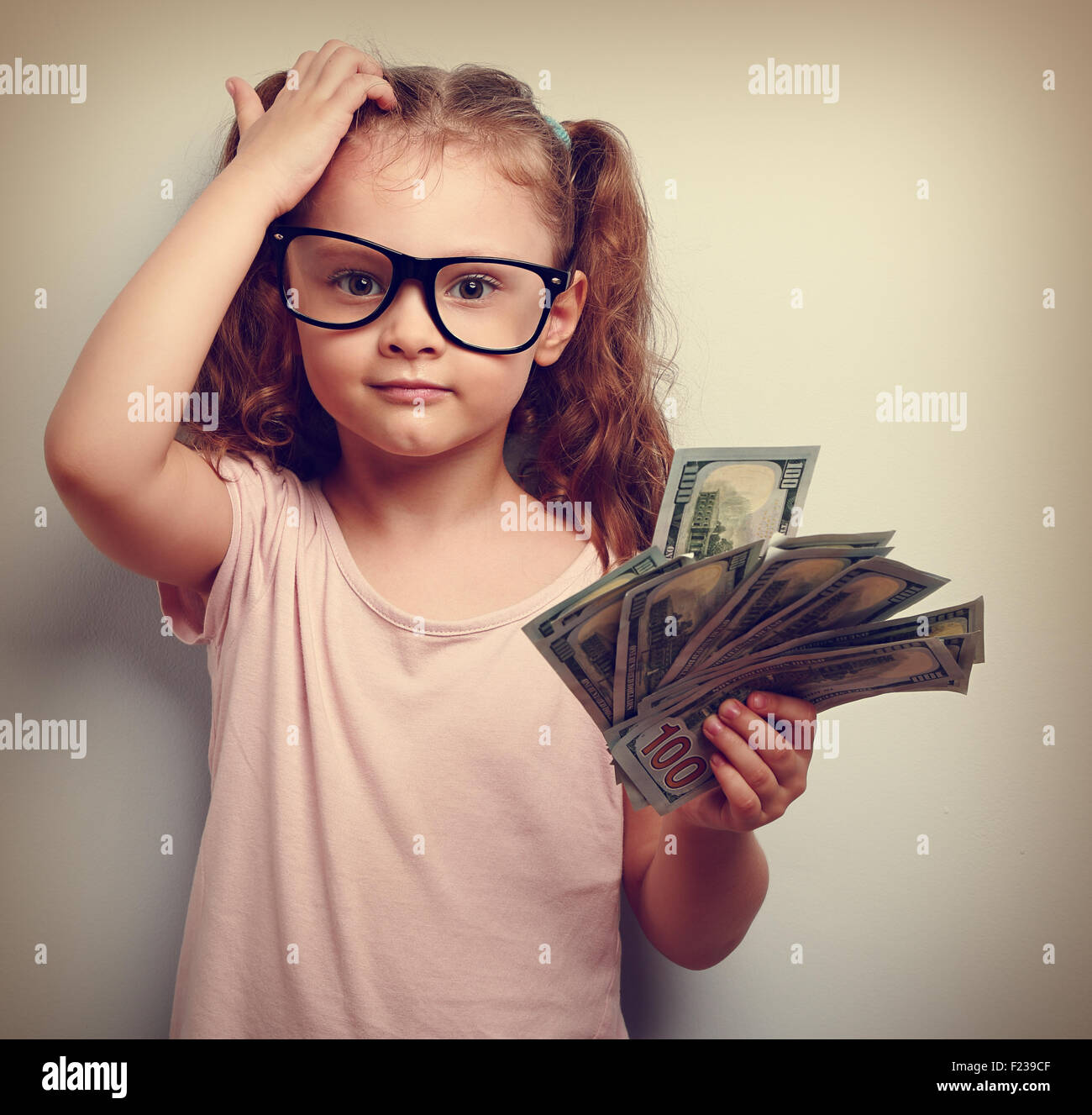 Small professor in eye glasses scratching head, holding money and ...