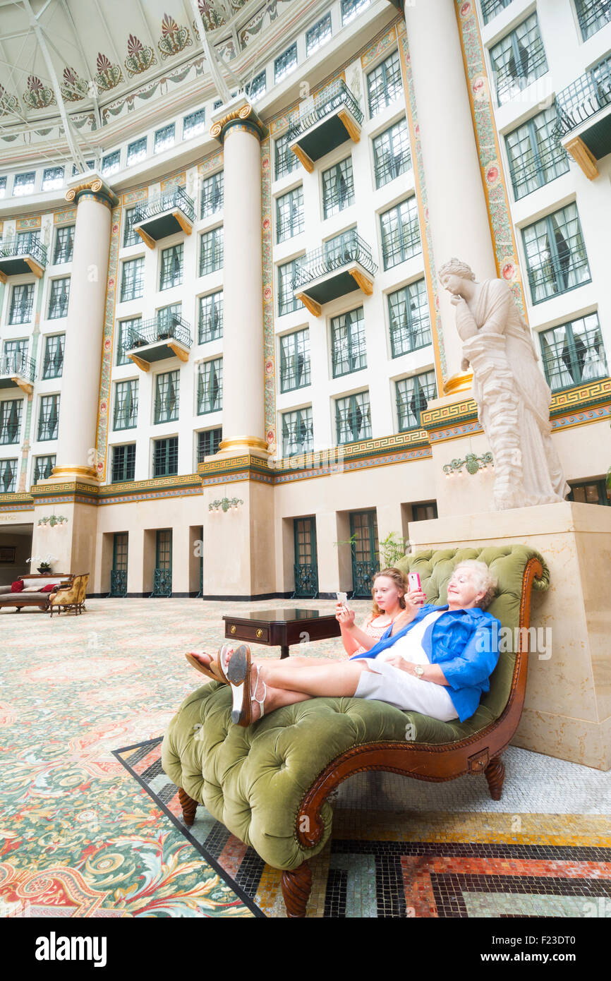 Senior woman and granddaughter looking at smartphones while sitting in ...