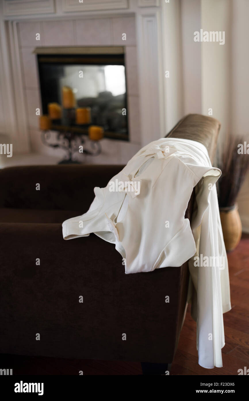 White dress draped over a brown suede chair in a room with a candelabra ...