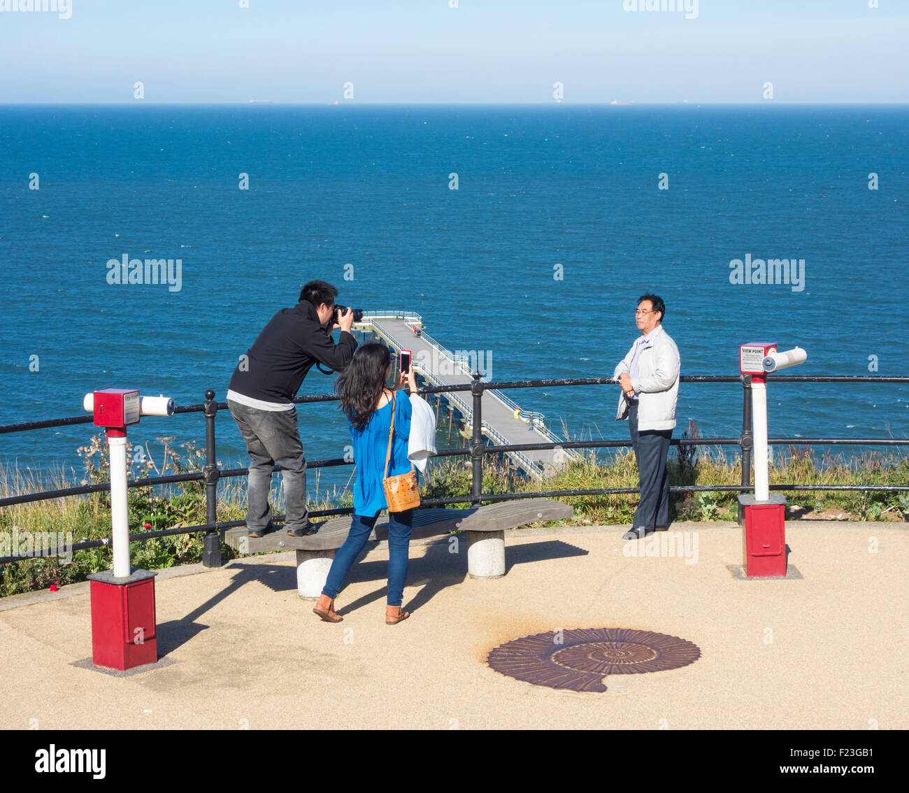 Chinese tourists taking photos overlooking beach and pier from top ...